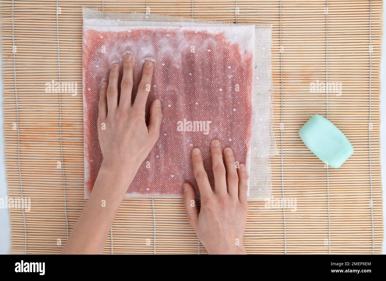 Using palms to gently rub net brushed with olive oil soap up and down ...