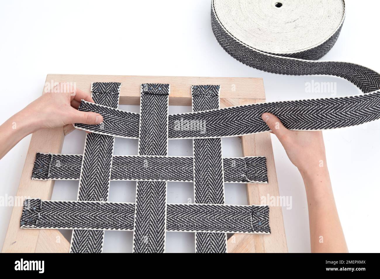 Weaving second set of upholstery webbing over and under the first webs ...