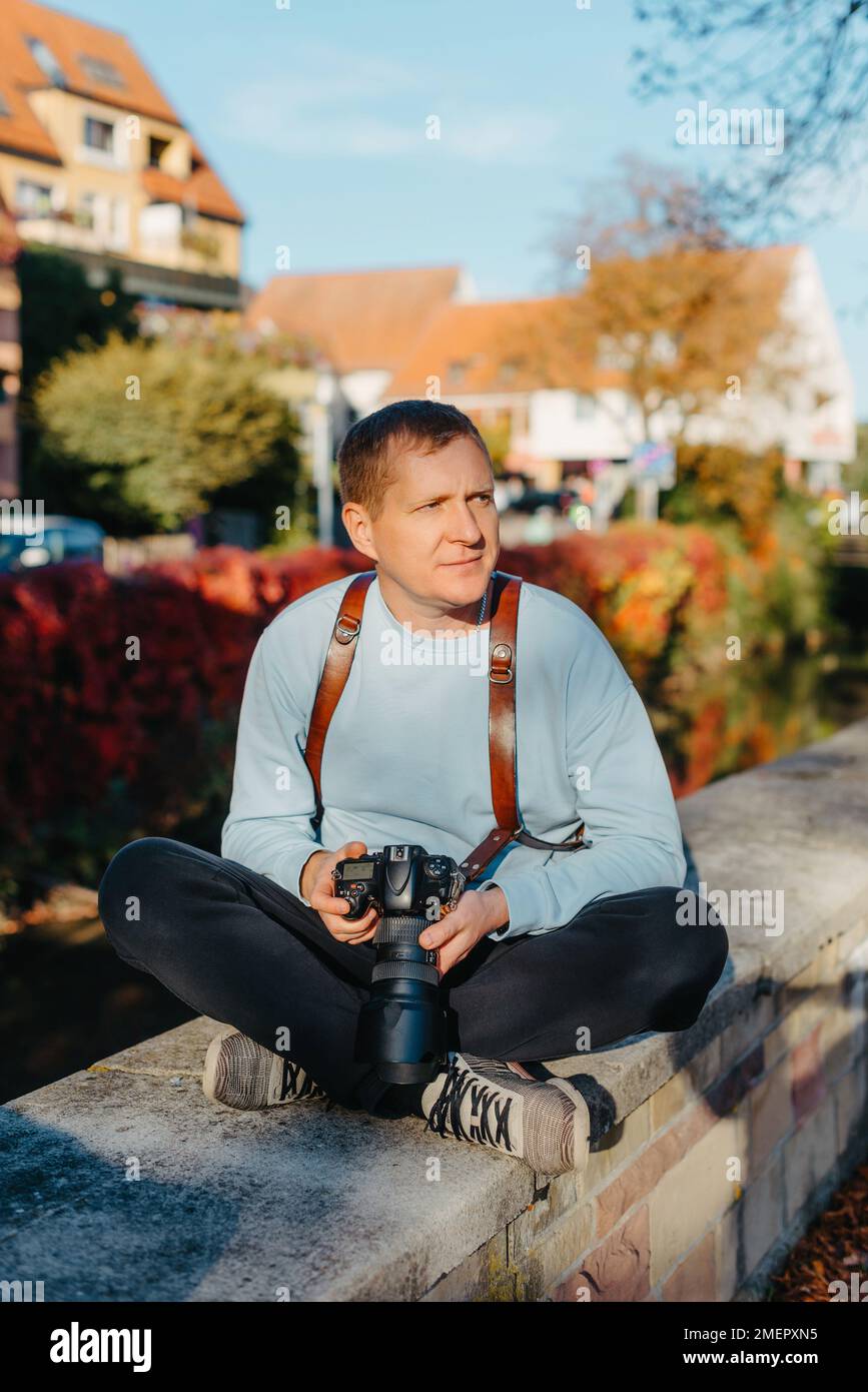 Man Sitting in Old European City And Holding Photo Camera. Contemporary ...