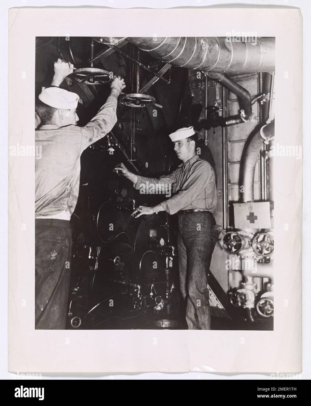 The engine room of a U.S. Navy cruiser is depicted, with crew members ...