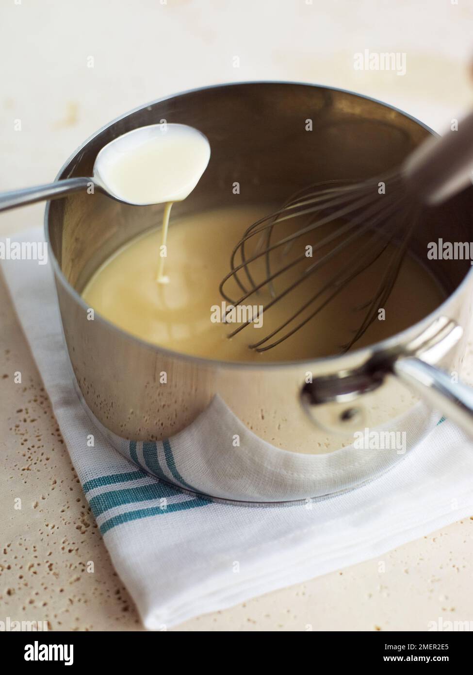 Cooking veloute sauce in saucepan, adding cream with spoon Stock Photo ...