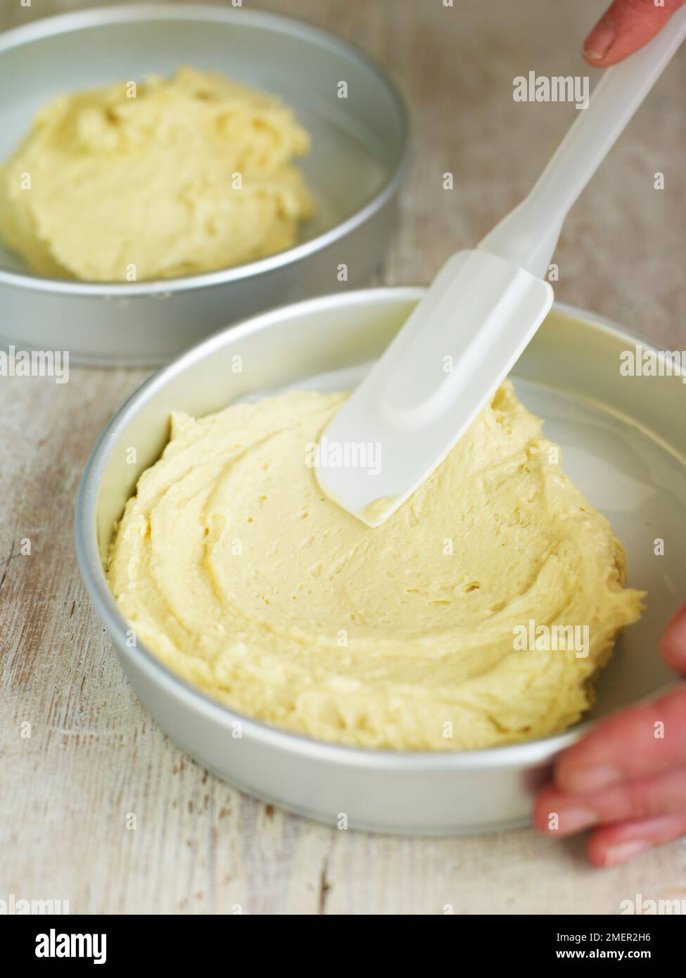 Spreading out Victoria sponge cake mixture in two tins, using a spatula ...
