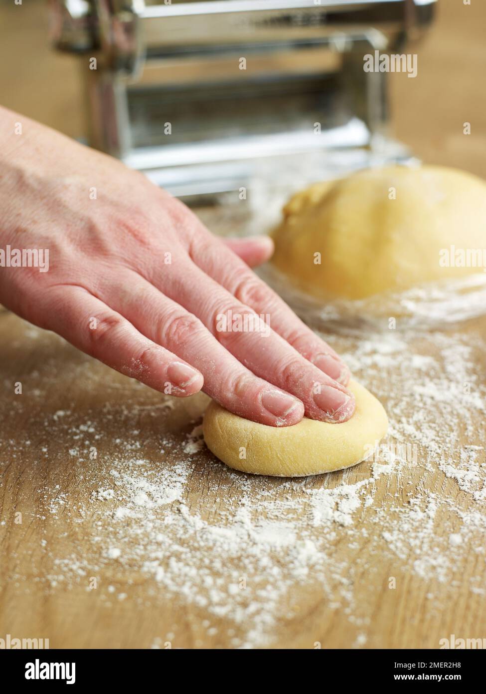 Flattening piece of pasta dough and covering both sides with flour ...