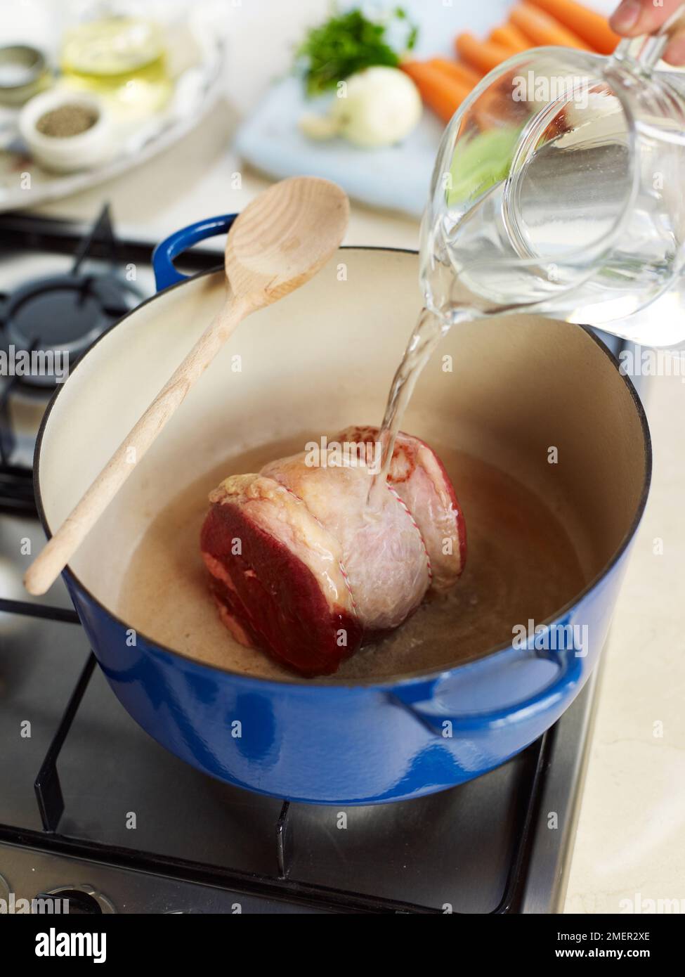 Pouring water over beef brisket in pan (making pot-au-feu Stock Photo ...