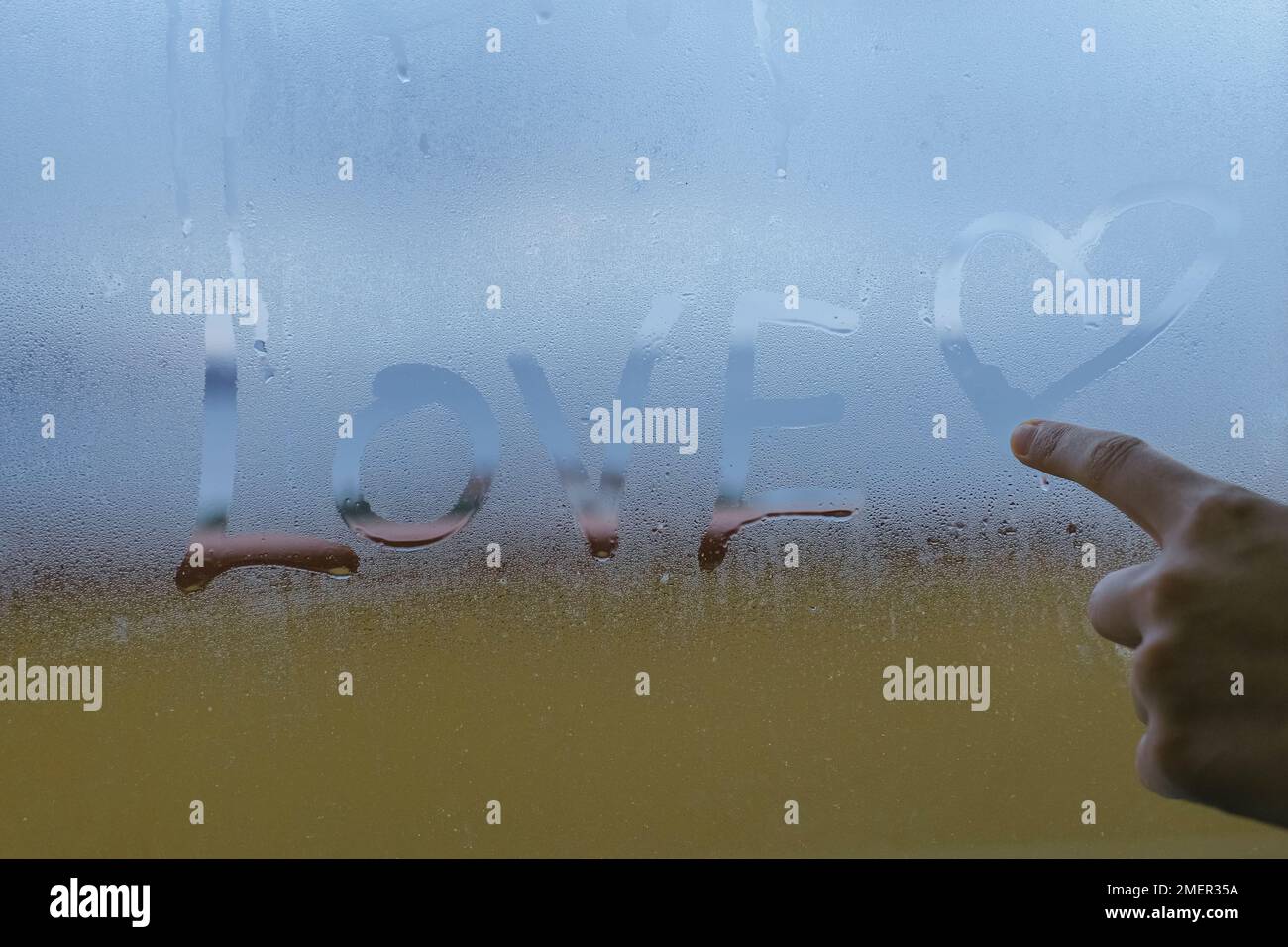 Woman hand writing love word sign on a foggy window glass, feelings ...