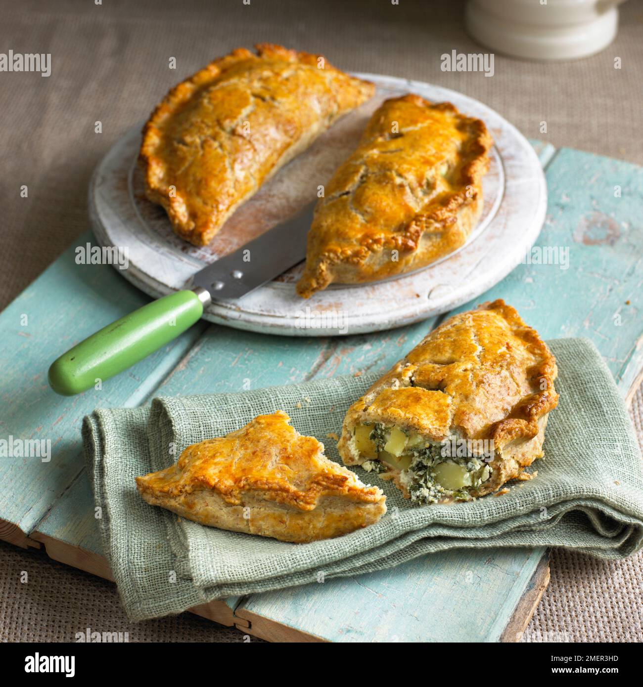 Wholemeal spinach and potato pasty broken in half showing filling, more ...