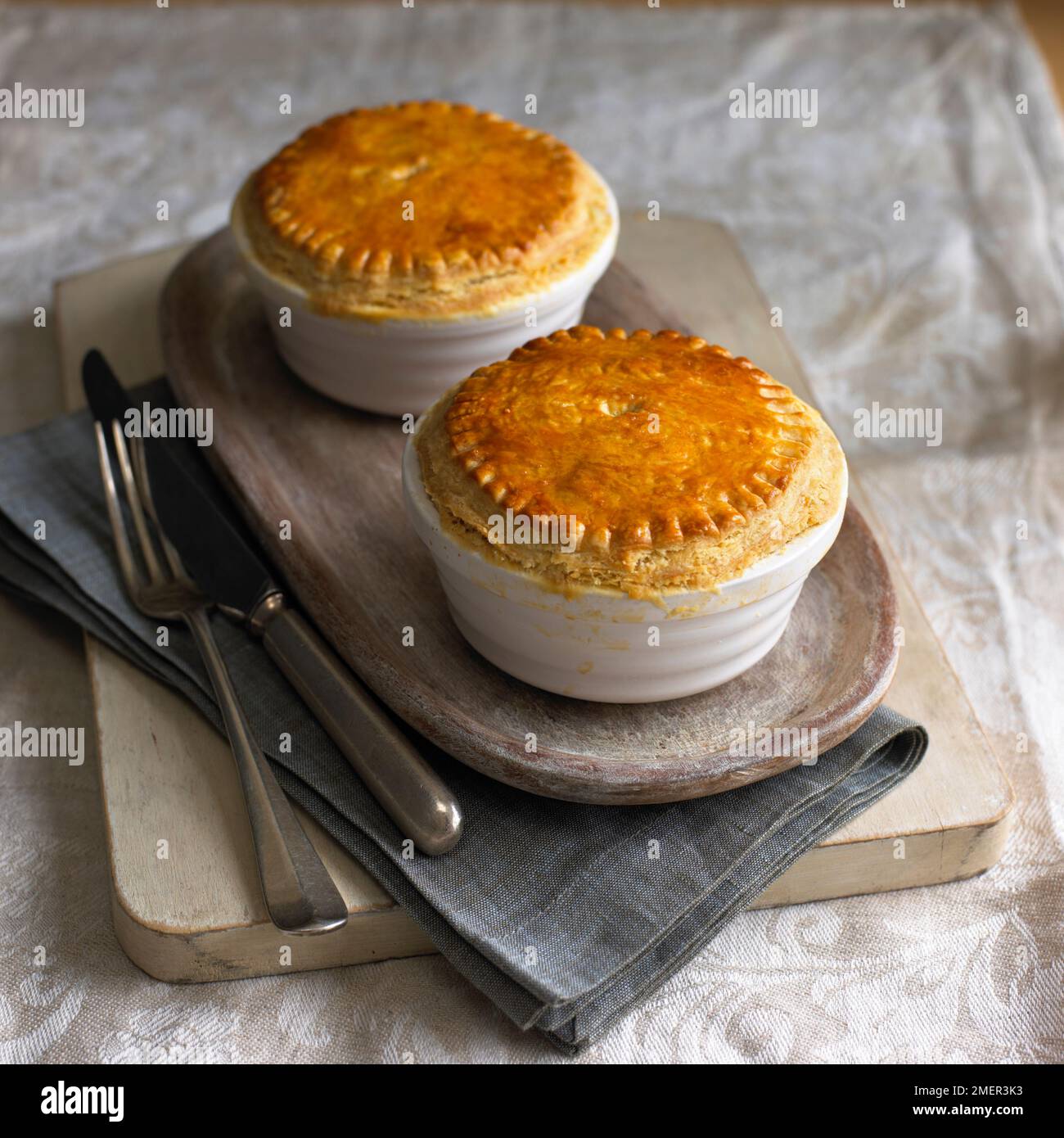 Two chicken pot pies on serving tray, with cutlery Stock Photo - Alamy