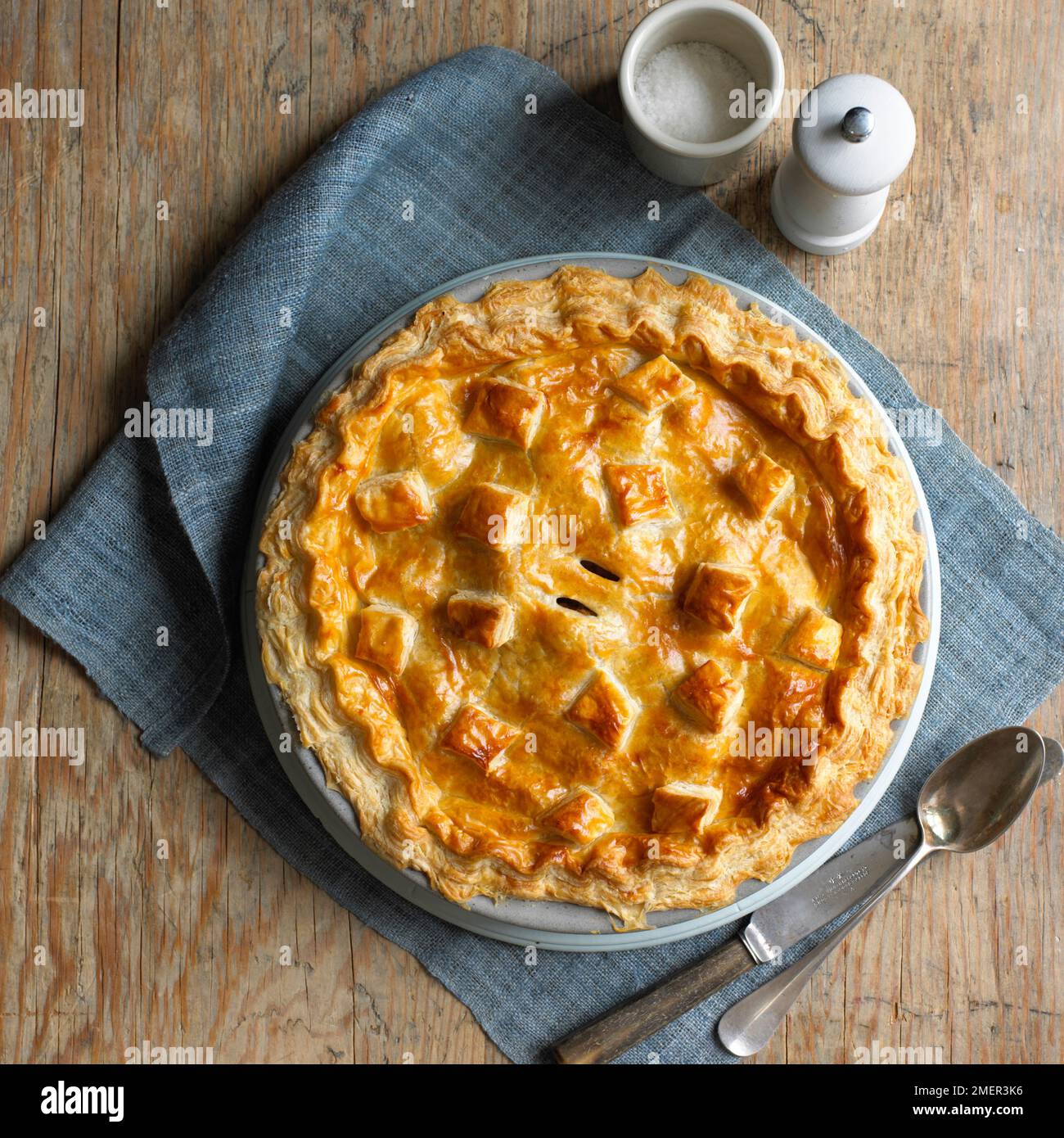 Wild mushroom and guinea fowl pie on table, with salt, pepper mill and ...