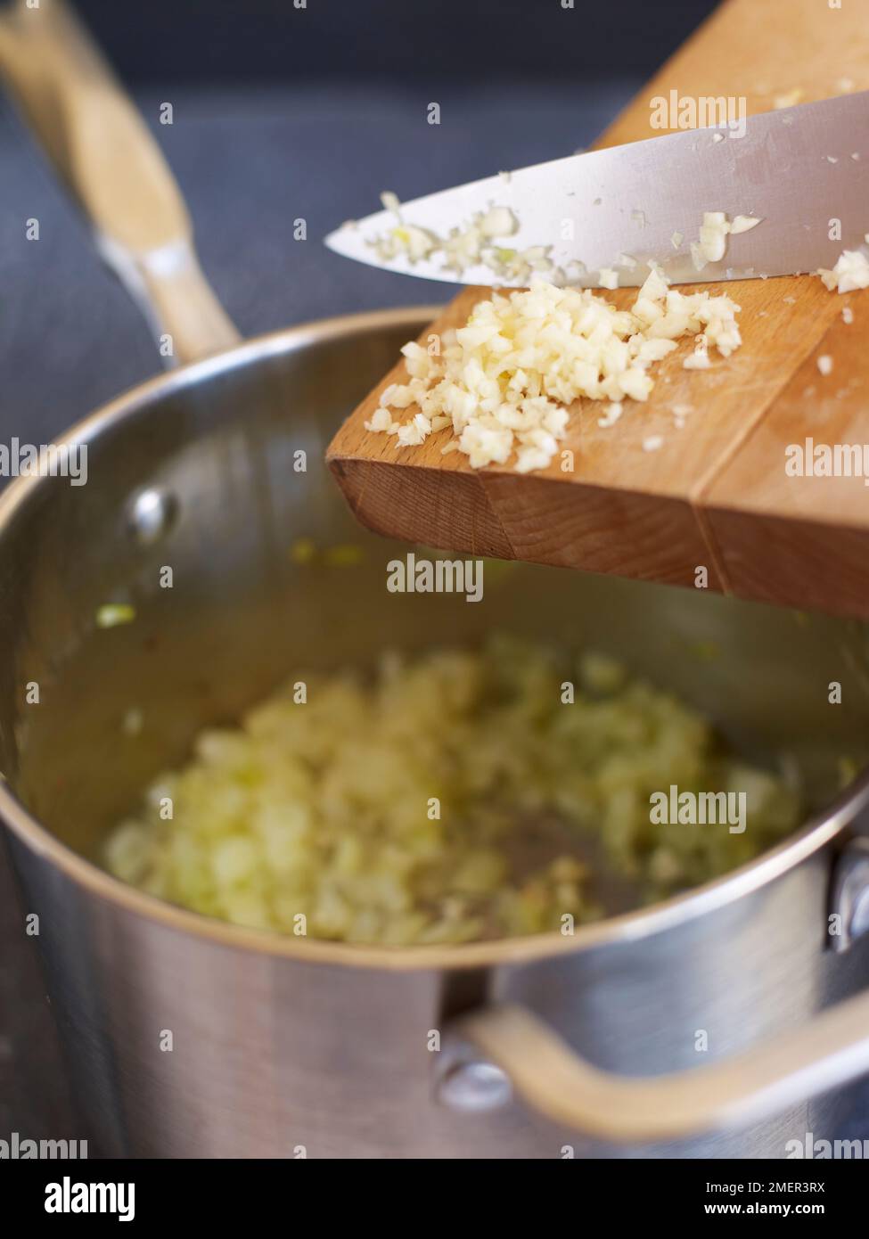 Adding chopped garlic to pan with onions Stock Photo - Alamy