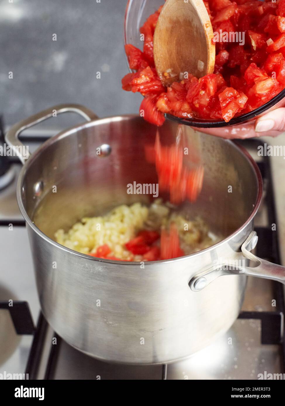 Adding chopped tomatoes to pan with onions (cooking tomato sauce Stock ...