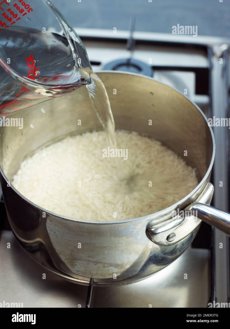 Covering rice in pan with twice the amount of cold water Stock Photo ...