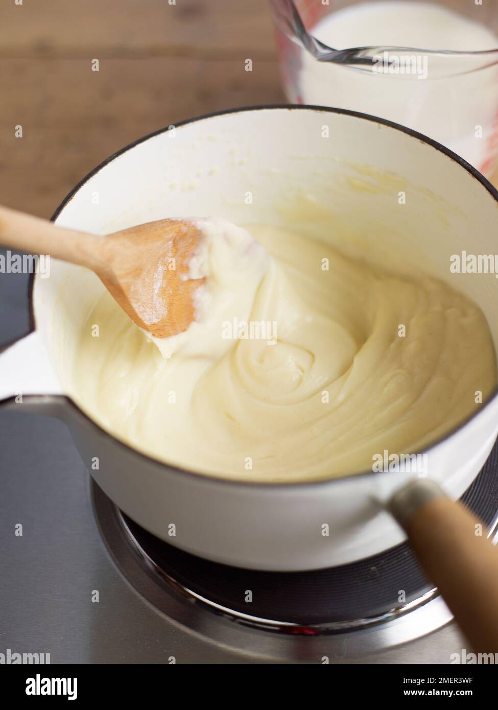 Mixing roux with milk, using wooden spoon (cooking bechamel sauce Stock ...