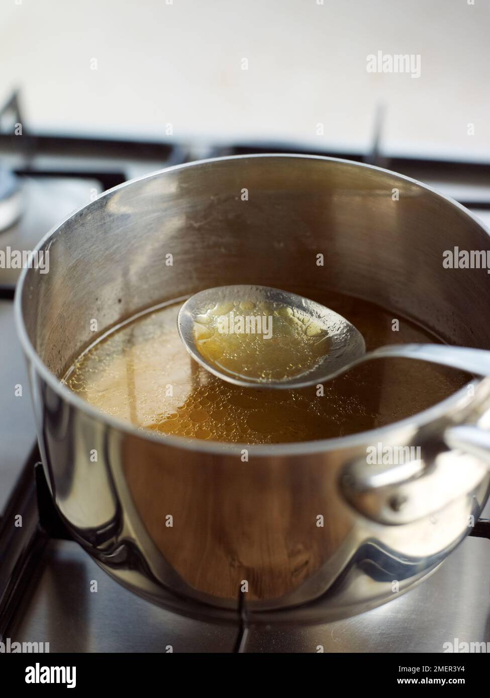 Skimming off scum from stock, using a spoon Stock Photo - Alamy