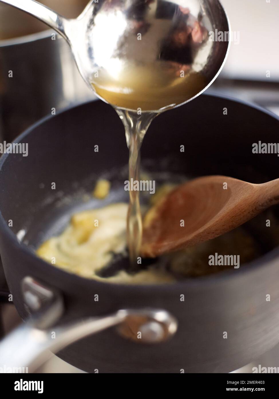 Pouring in stock and mixing with roux (cooking veloute sauce Stock ...
