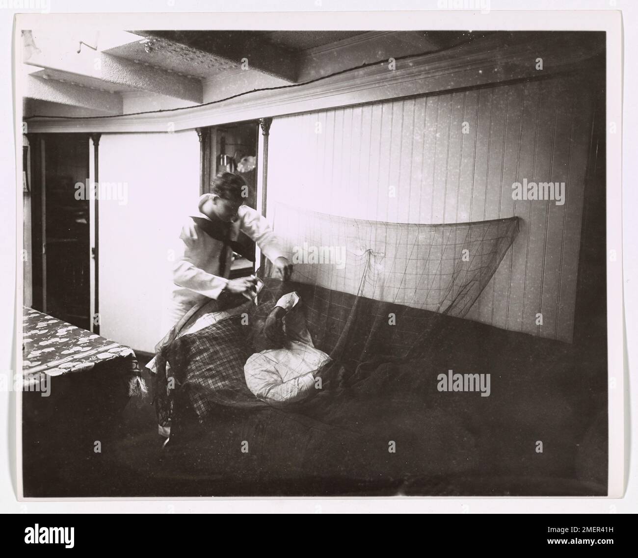This photograph depicts two Coast Guardsmen aboard a ship, with one ...