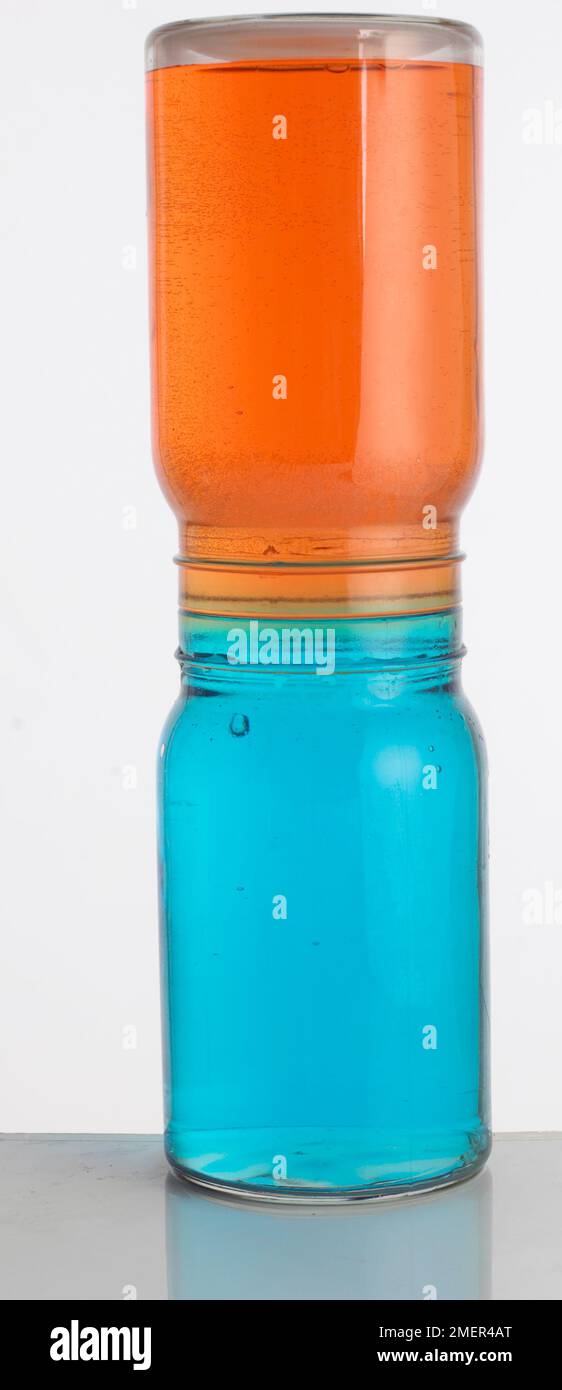 Jar of blue water with a jar of red water upside down on top Stock ...