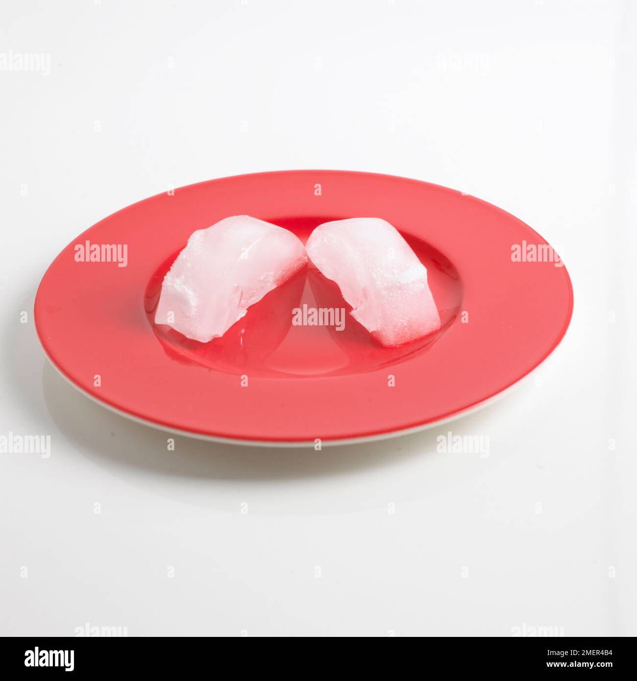 Red plate holding two ice cubes Stock Photo - Alamy