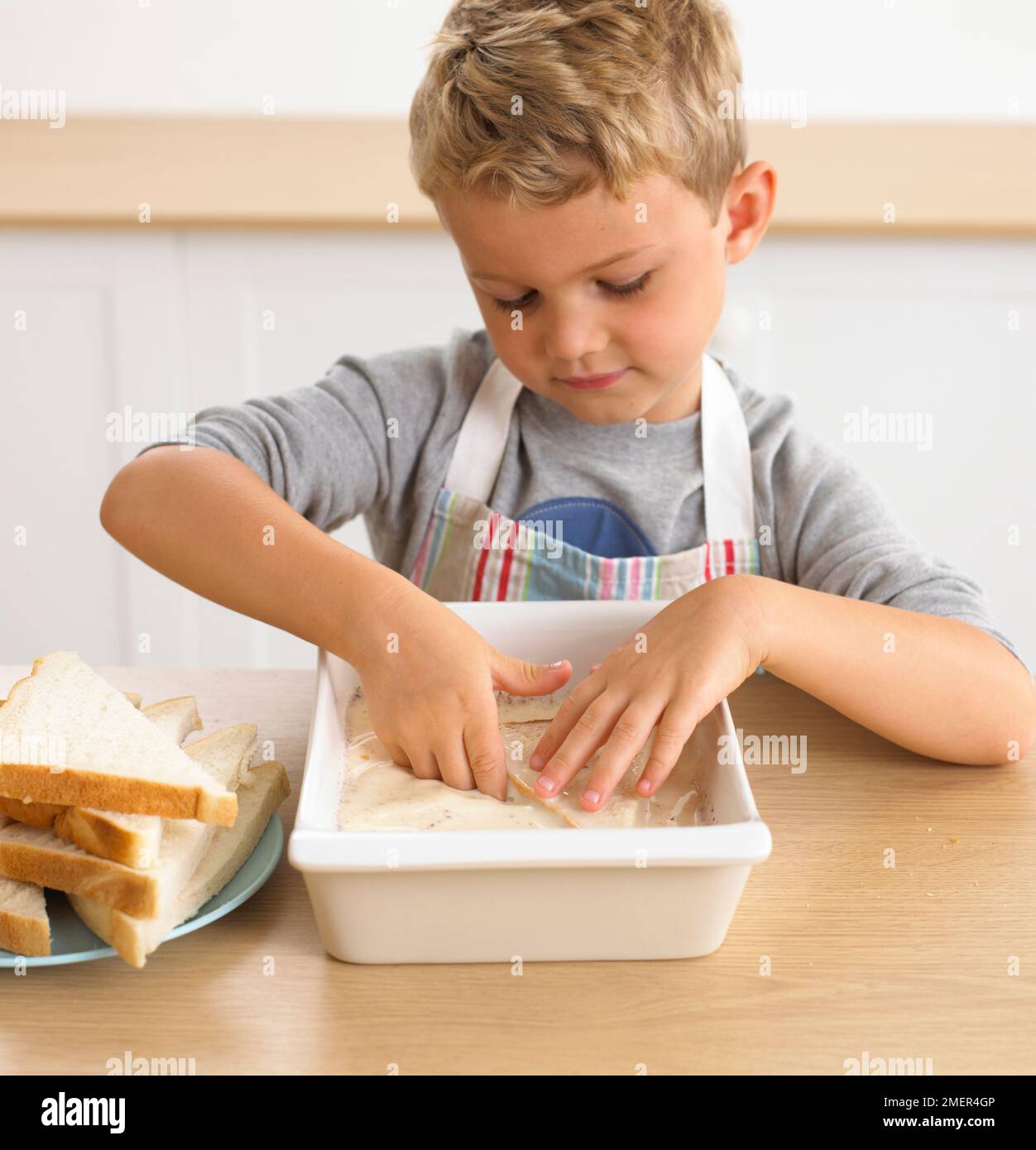 Boy soaking bread triangles in shallow dish, 4 years Stock Photo - Alamy