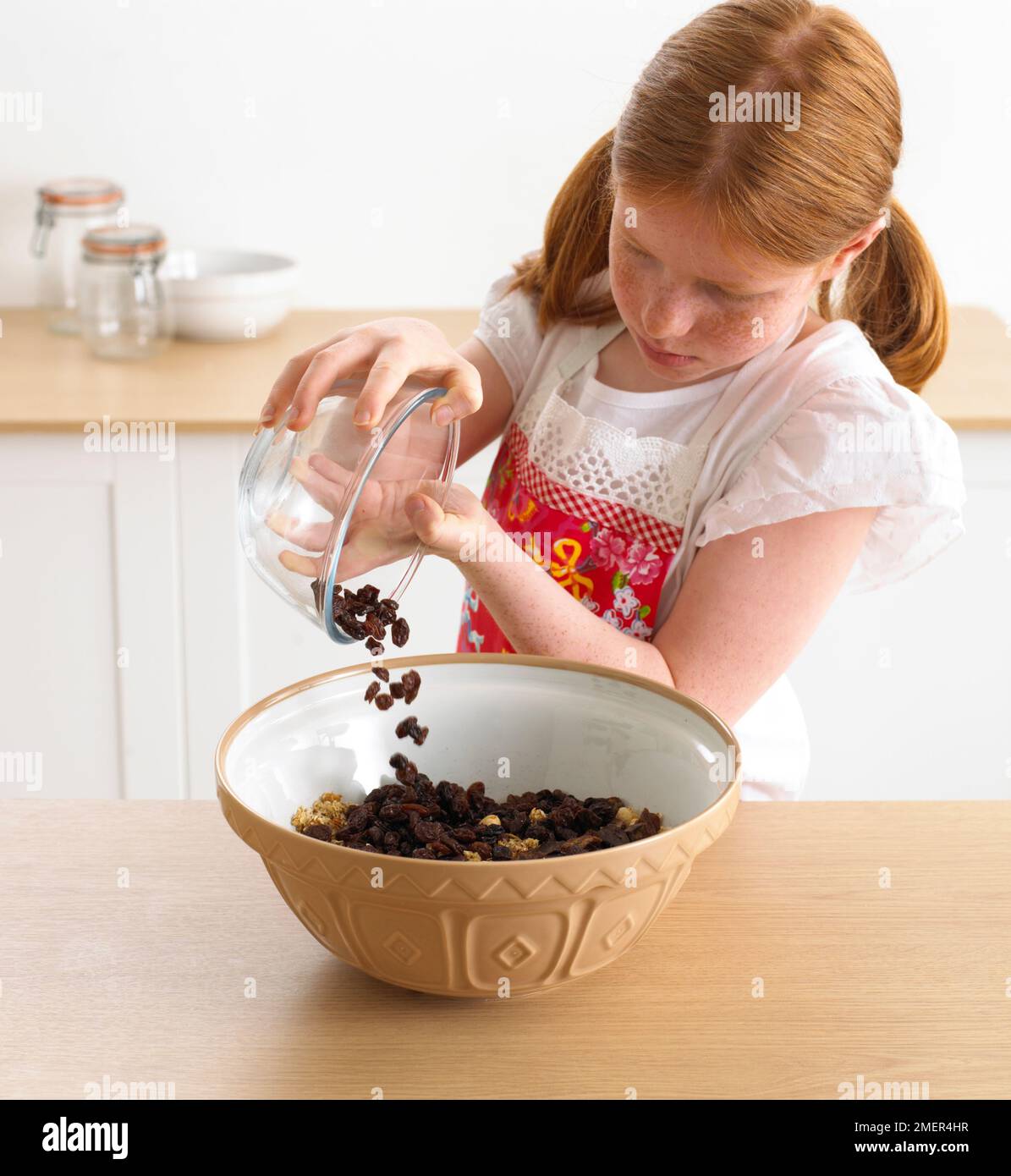 Girl pouring bowl of raisins to bowl of cereal, 9 years Stock Photo - Alamy