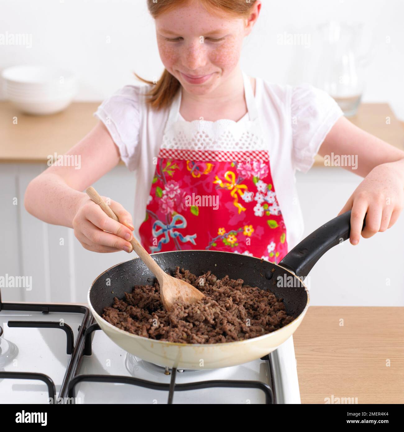 Girl frying mince beef in a pan, 9 years Stock Photo - Alamy