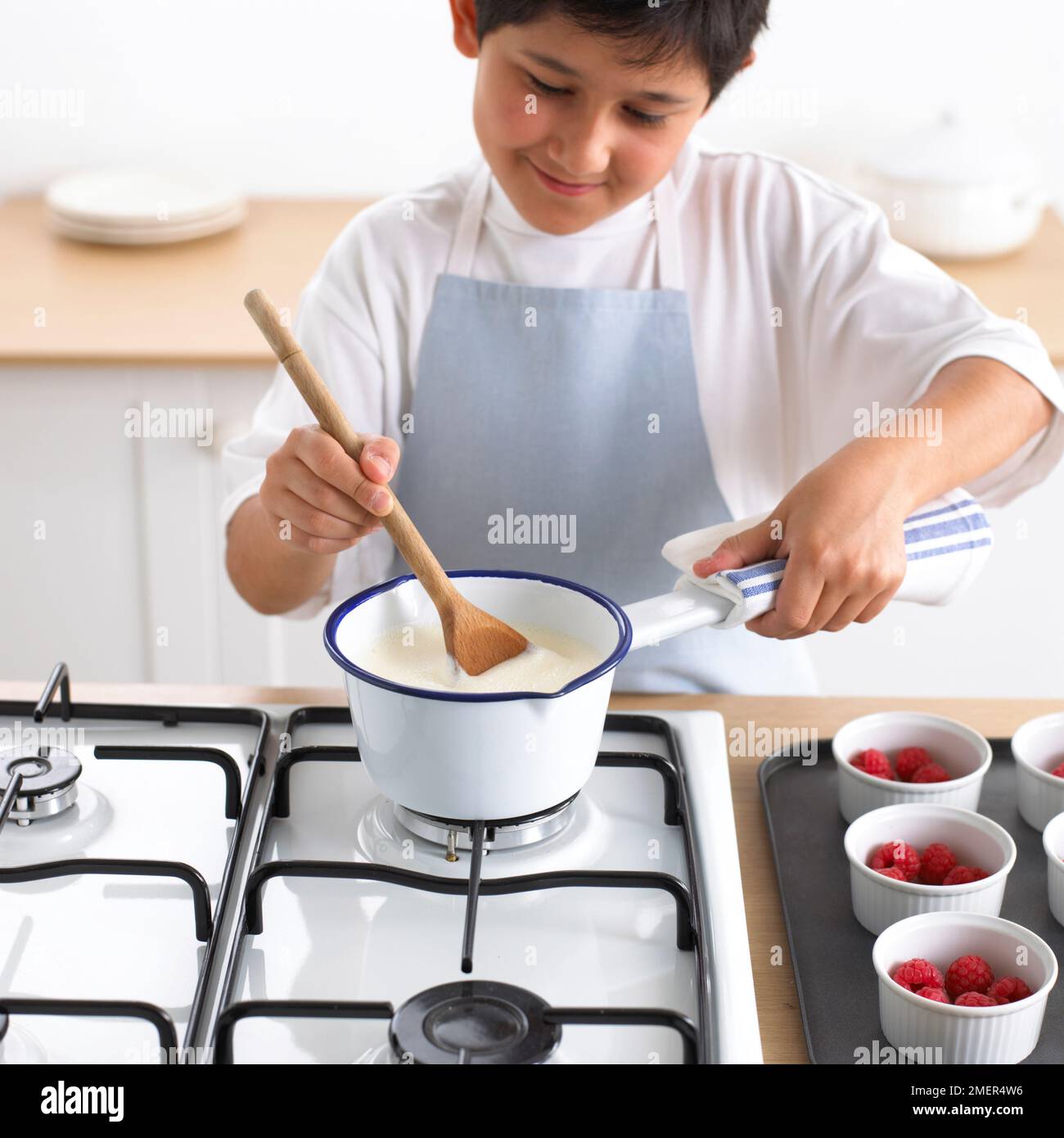 Boy cooking custard in a saucepan, 9 years Stock Photo - Alamy