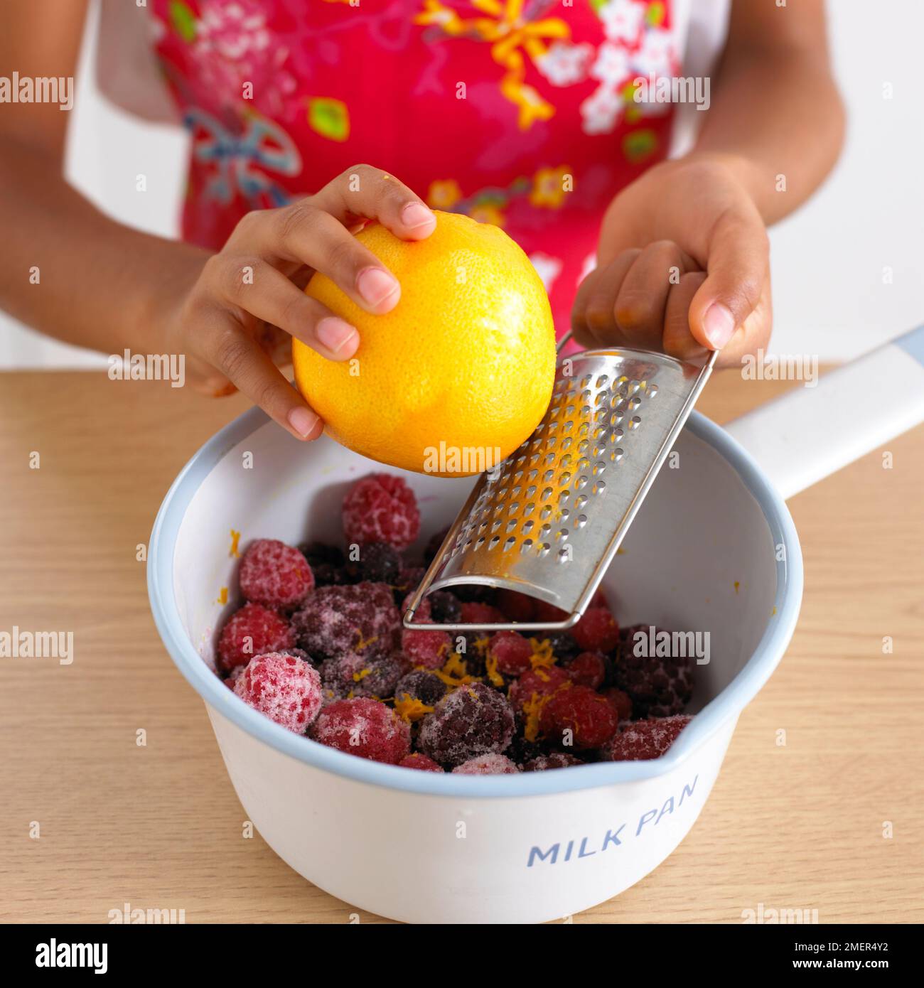 Grating orange zest into bowl of strawberries Stock Photo - Alamy