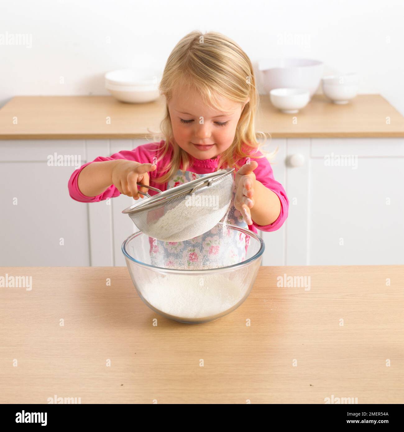 Girl sieving flour into a bowl, 3 years Stock Photo - Alamy