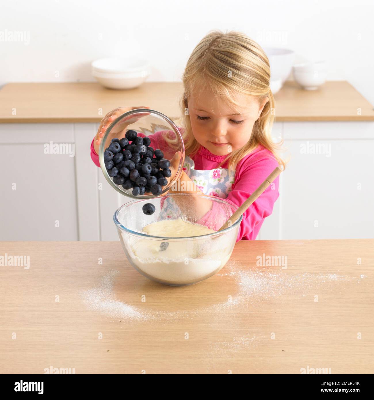 Girl pouring in blueberries into muffin mixture, 3 years Stock Photo ...