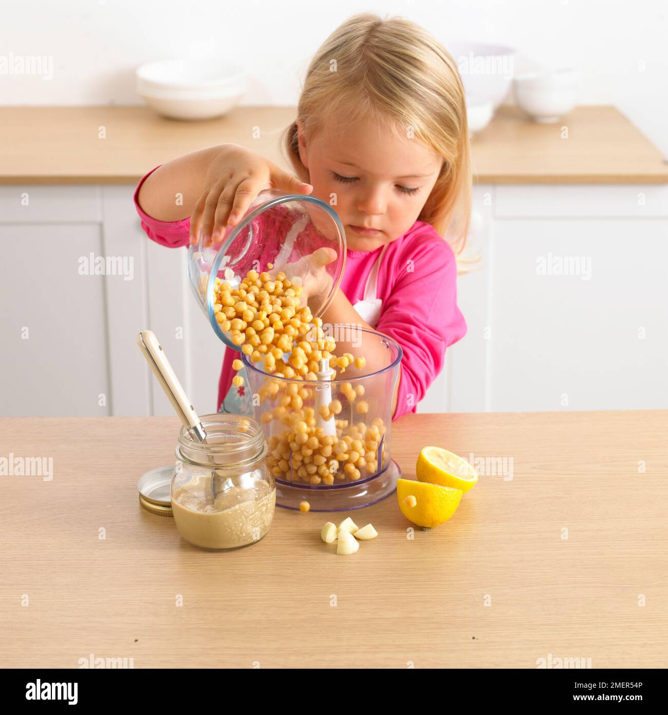 Girl pouring chickpeas into food processor, 3 years Stock Photo - Alamy