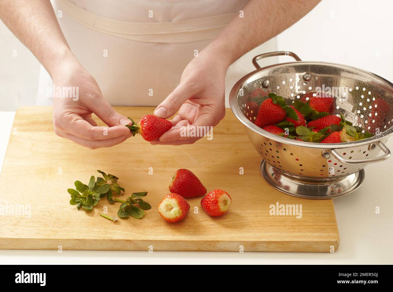 Cutting stalk from strawberry and placing in colander Stock Photo - Alamy