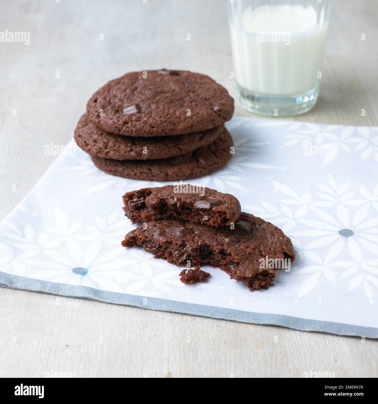 Three chocolate chip cookies and glass of milk Stock Photo - Alamy