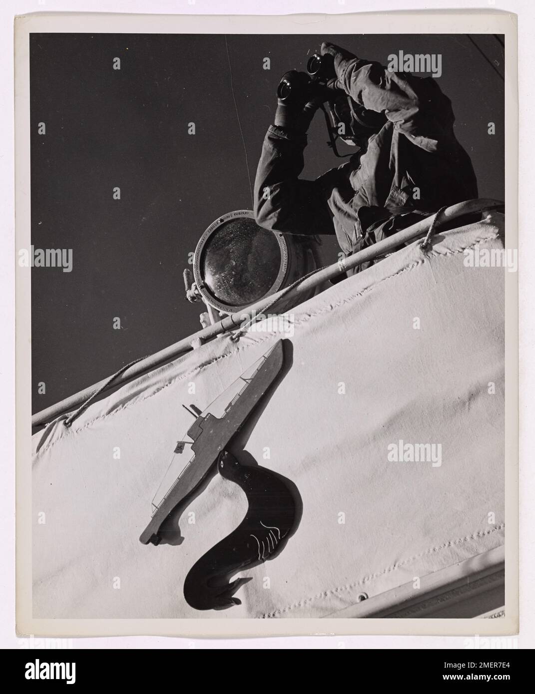 A Coast Guardsman scans the skies with binoculars, vigilantly searching ...