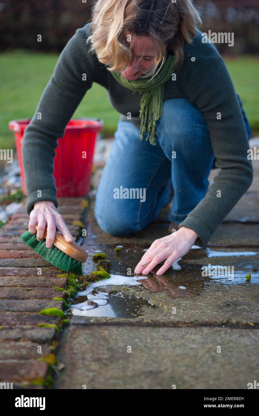 Removing moss from a path with a scrubbing brush Stock Photo - Alamy