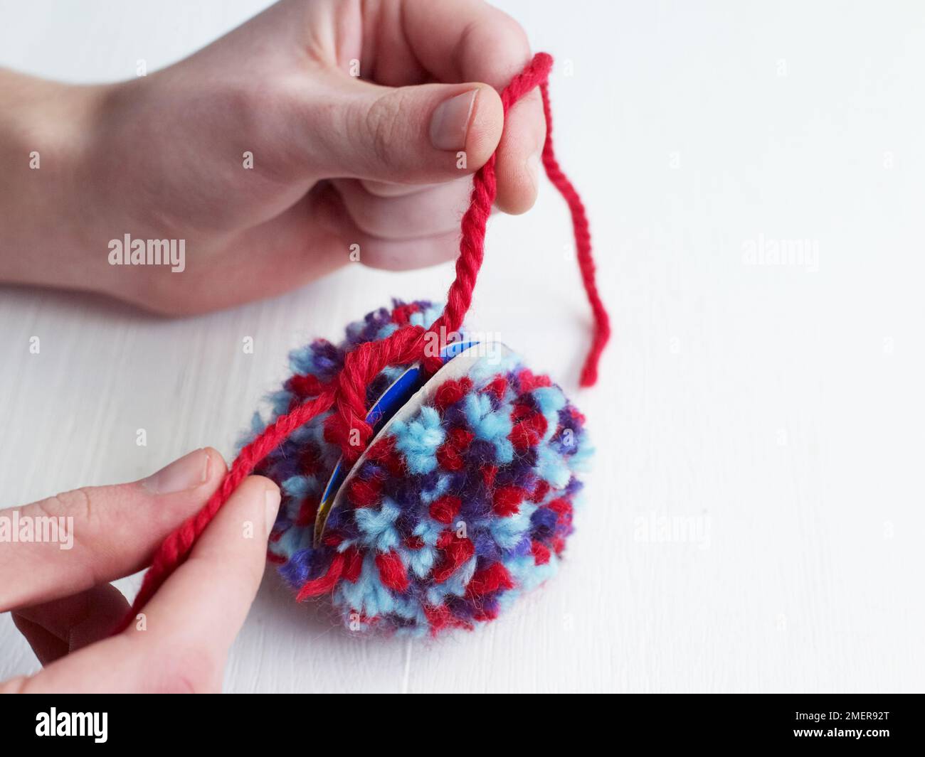 Making pom-pom, tying length of wool between two card circles Stock ...