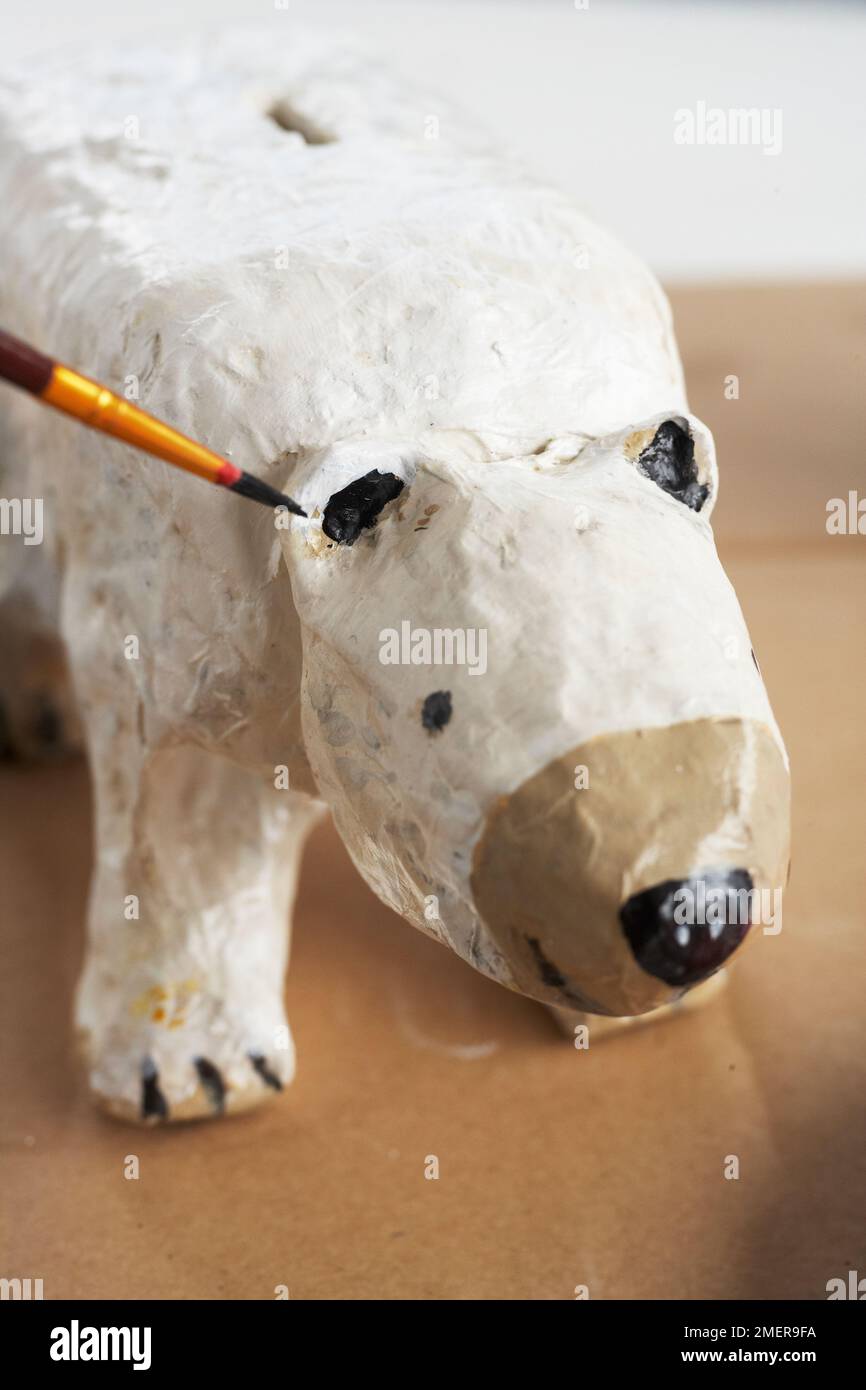 Painting ears on papier-mache polar bear piggy bank Stock Photo - Alamy