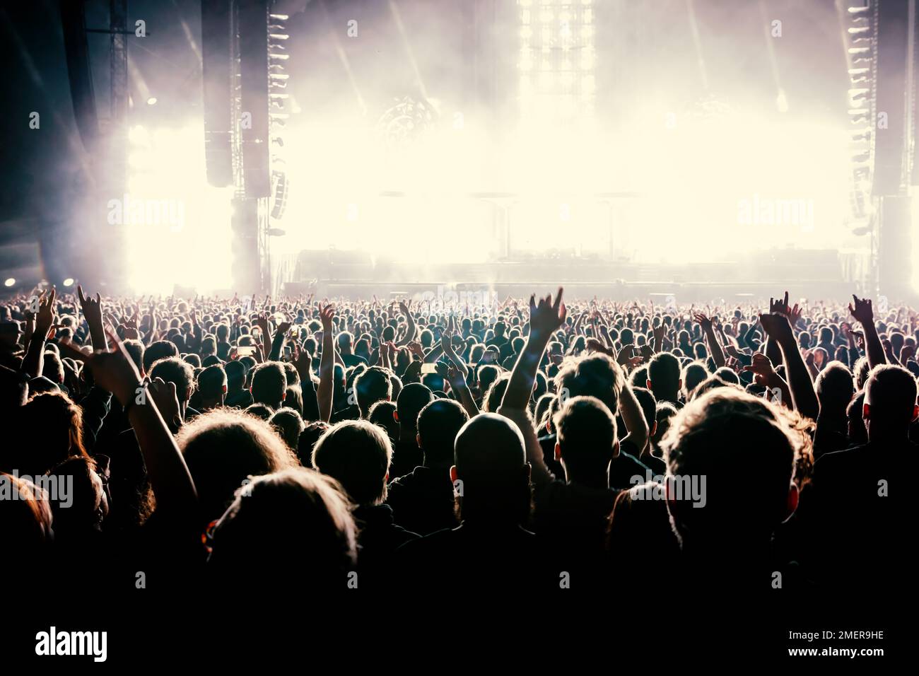 A crowd of people with raised arms during a music concert with an ...