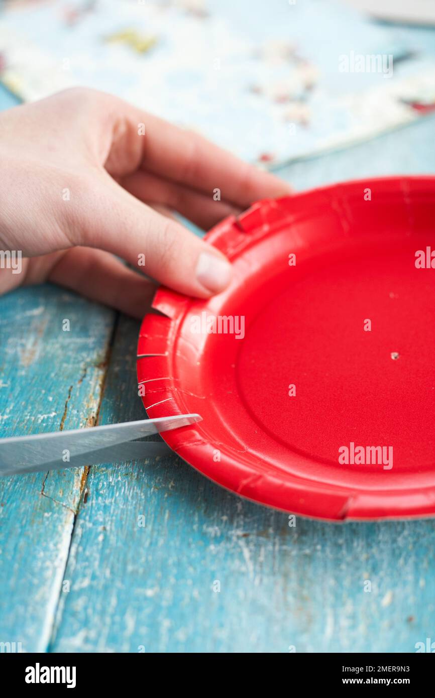 Making cuts all around edge of red paper plate, making paper birdcage ...