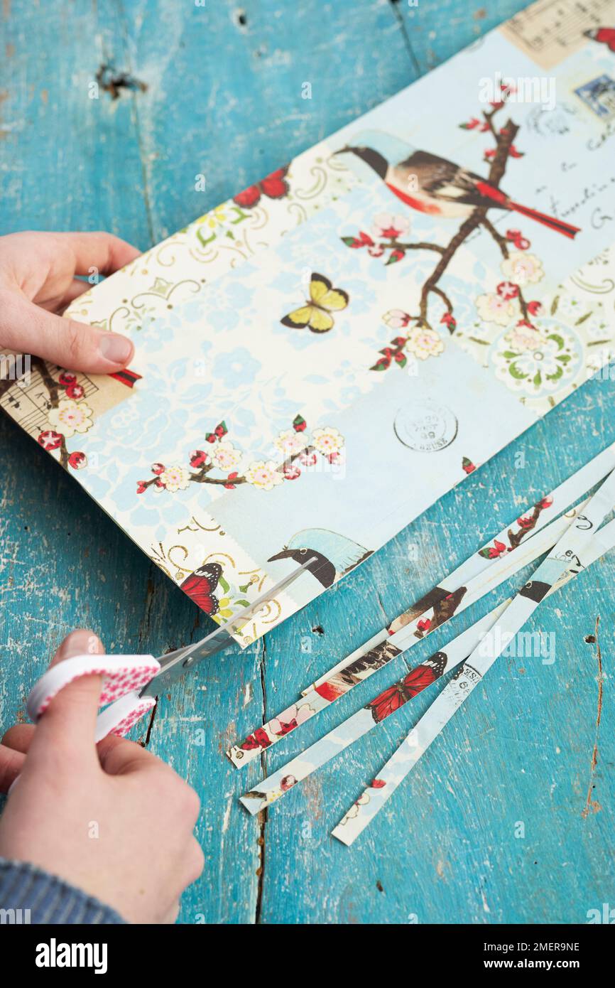 Cutting strips from card covered in patterned wrapping paper, making ...