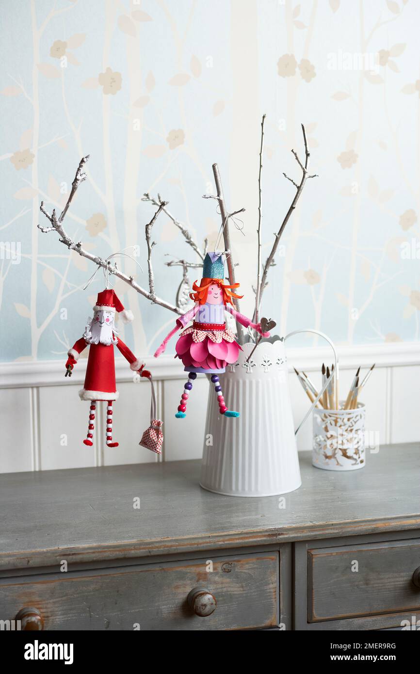 Paper fairy and Father Christmas decorations hanging from twigs Stock ...