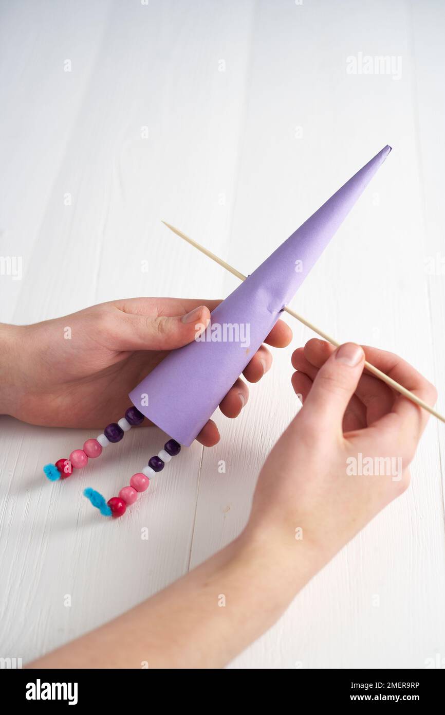 Making paper fairy decoration, using wooden skewer to make hole through ...