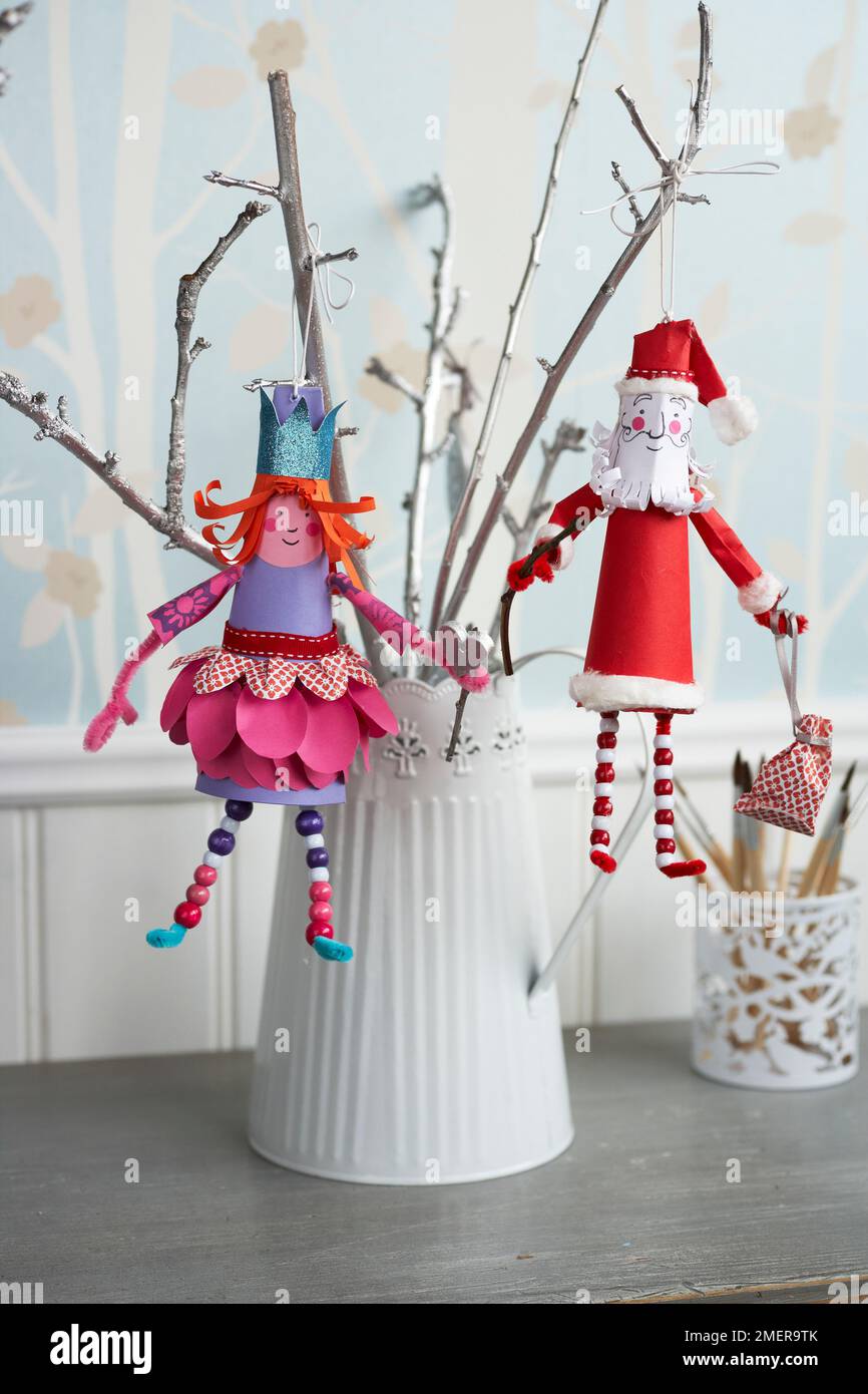 Paper fairy and Father Christmas decorations hanging from twigs Stock ...