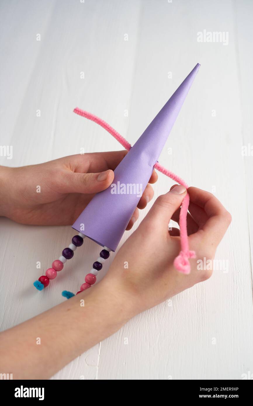 Making paper fairy decoration, threading pipe cleaner through holes ...