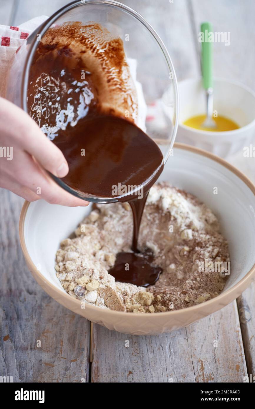 Pouring melted chocolate into the mixture, making brownies Stock Photo ...