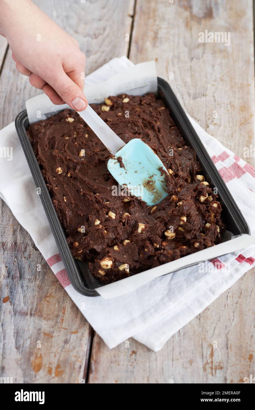 Smoothing over brownie mixture with spatula Stock Photo - Alamy