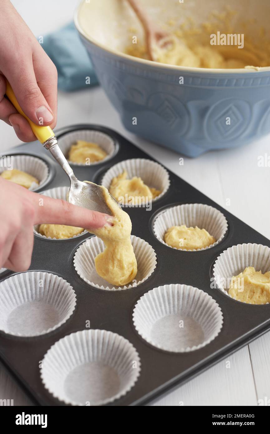Spooning cupcake mixture into paper cases Stock Photo - Alamy