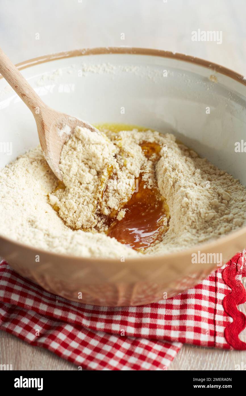 Stirring in golden syrup and egg and mixing together, making ...