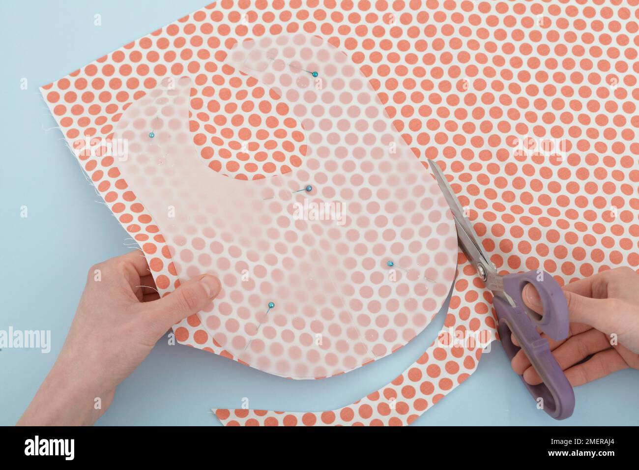 Making a bib, pin pattern to fabric and cut out with scissors Stock ...