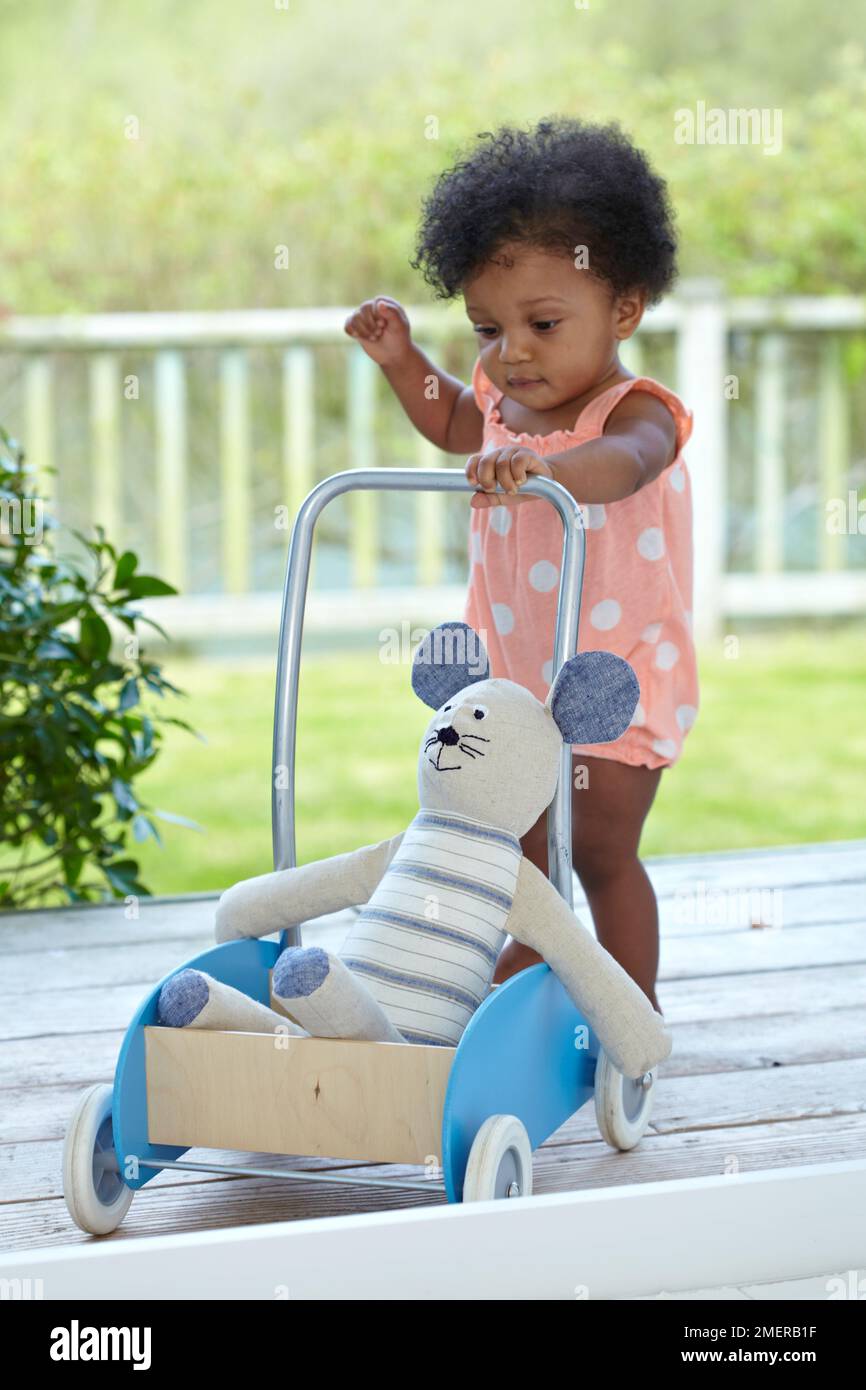 Toddler pushing soft toy mouse in push along trolley, 9 months Stock ...