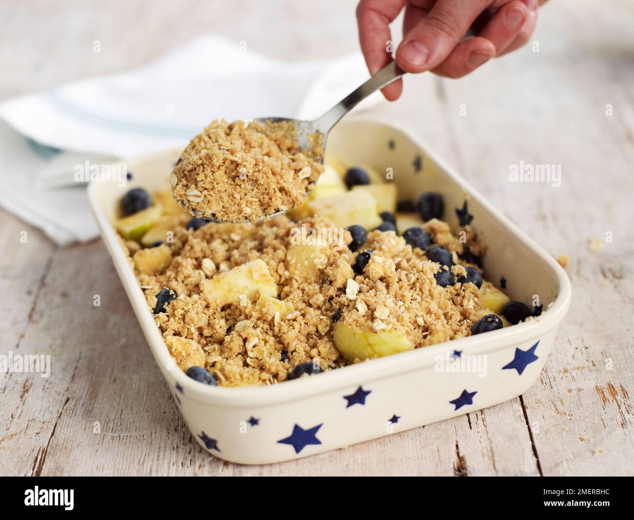 Apple and grape crumble bake, adding crumbs into pie dish Stock Photo ...