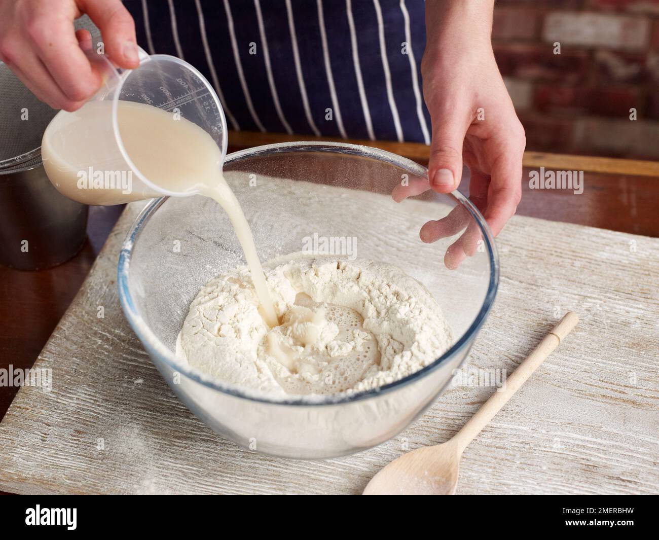 Making bread, pouring diluted yeast into large bowl with flour Stock ...